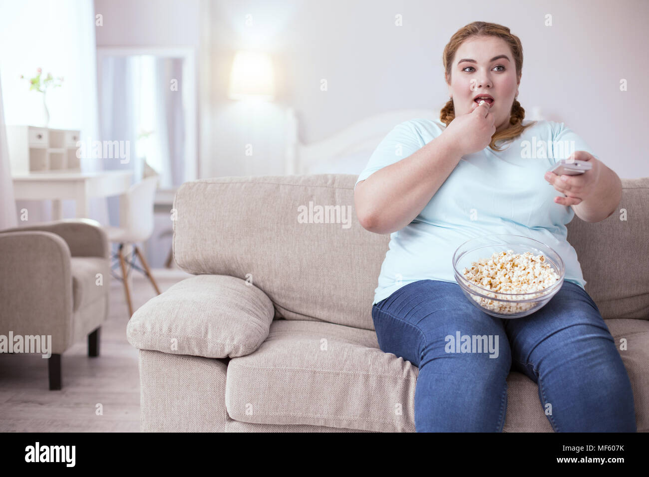 Thoughtful plump woman watching television Stock Photo - Alamy
