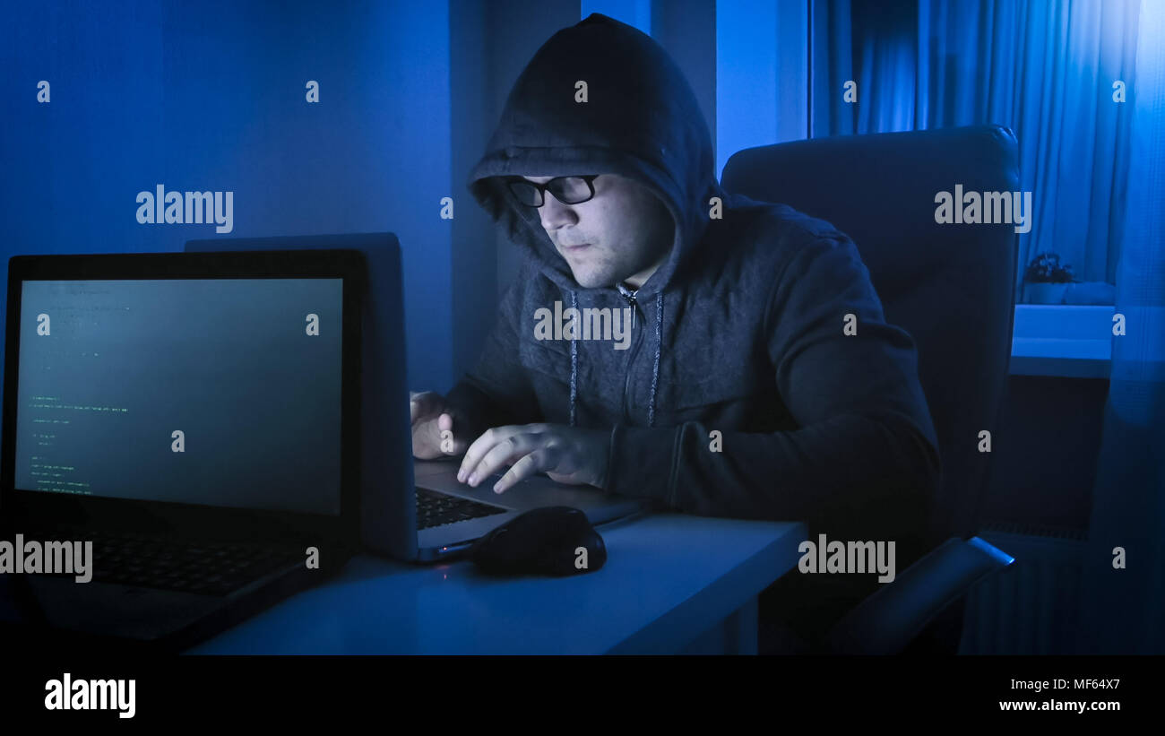 Portrait of concentrated hacker typing code of computer virus on laptop at night Stock Photo - Alamy