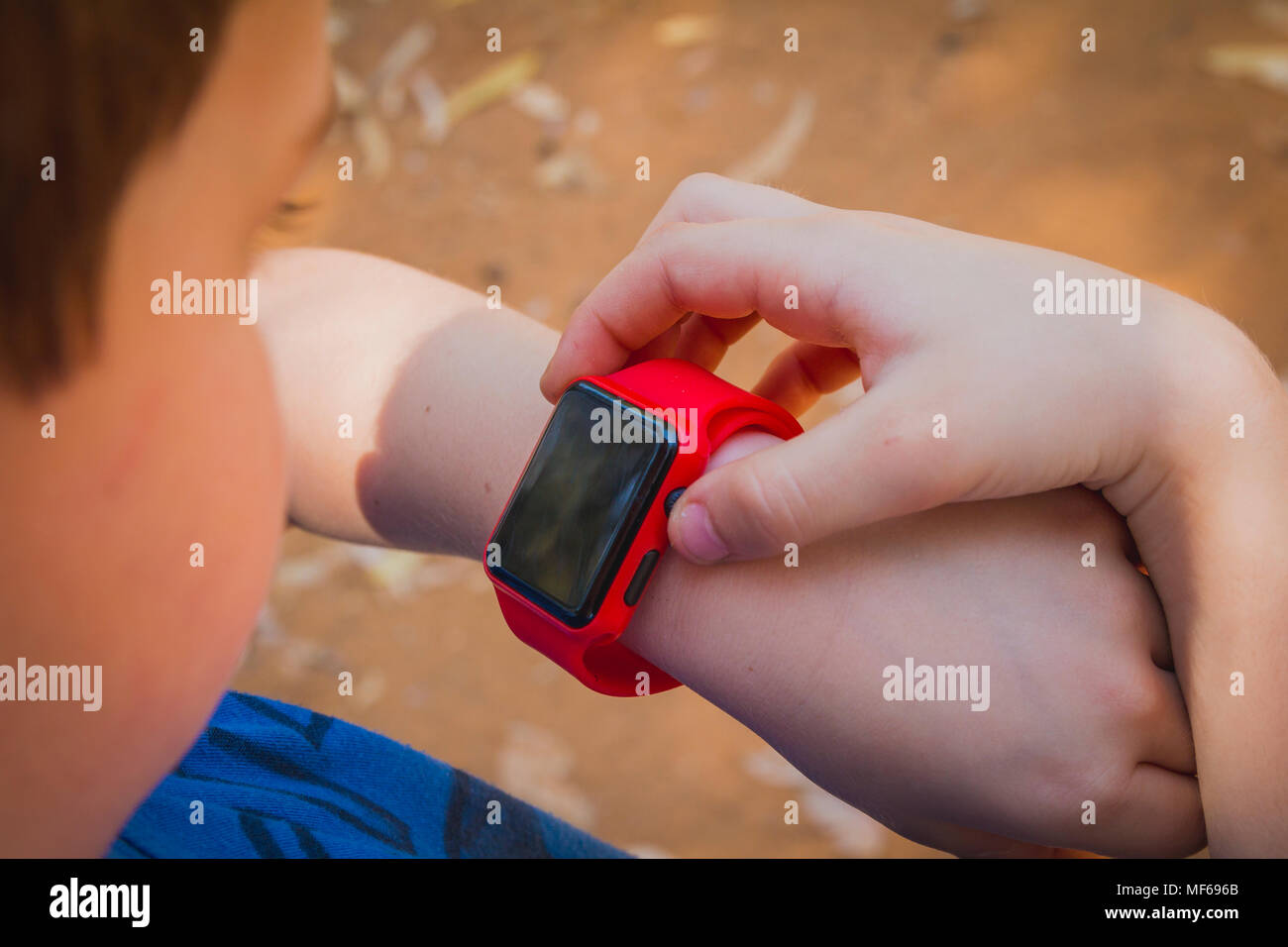Cute young boy looking at his red smart watch and touching it Stock ...