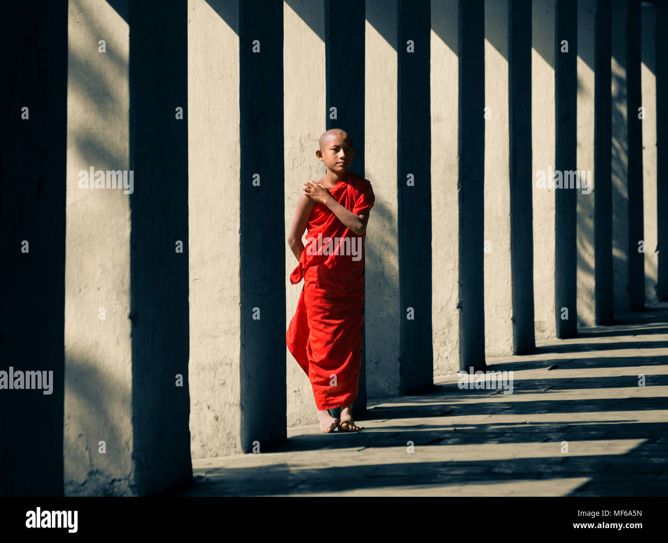 Novice Buddhist monk standing in eastern stair way of Shwezigon Pagoda ...