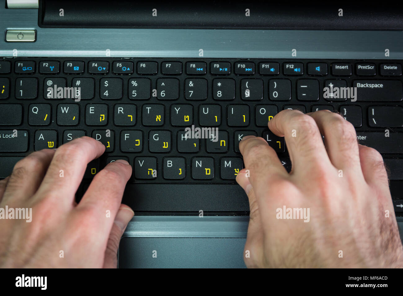 Man typing on a keyboard with letters in Hebrew and English - Laptop ...