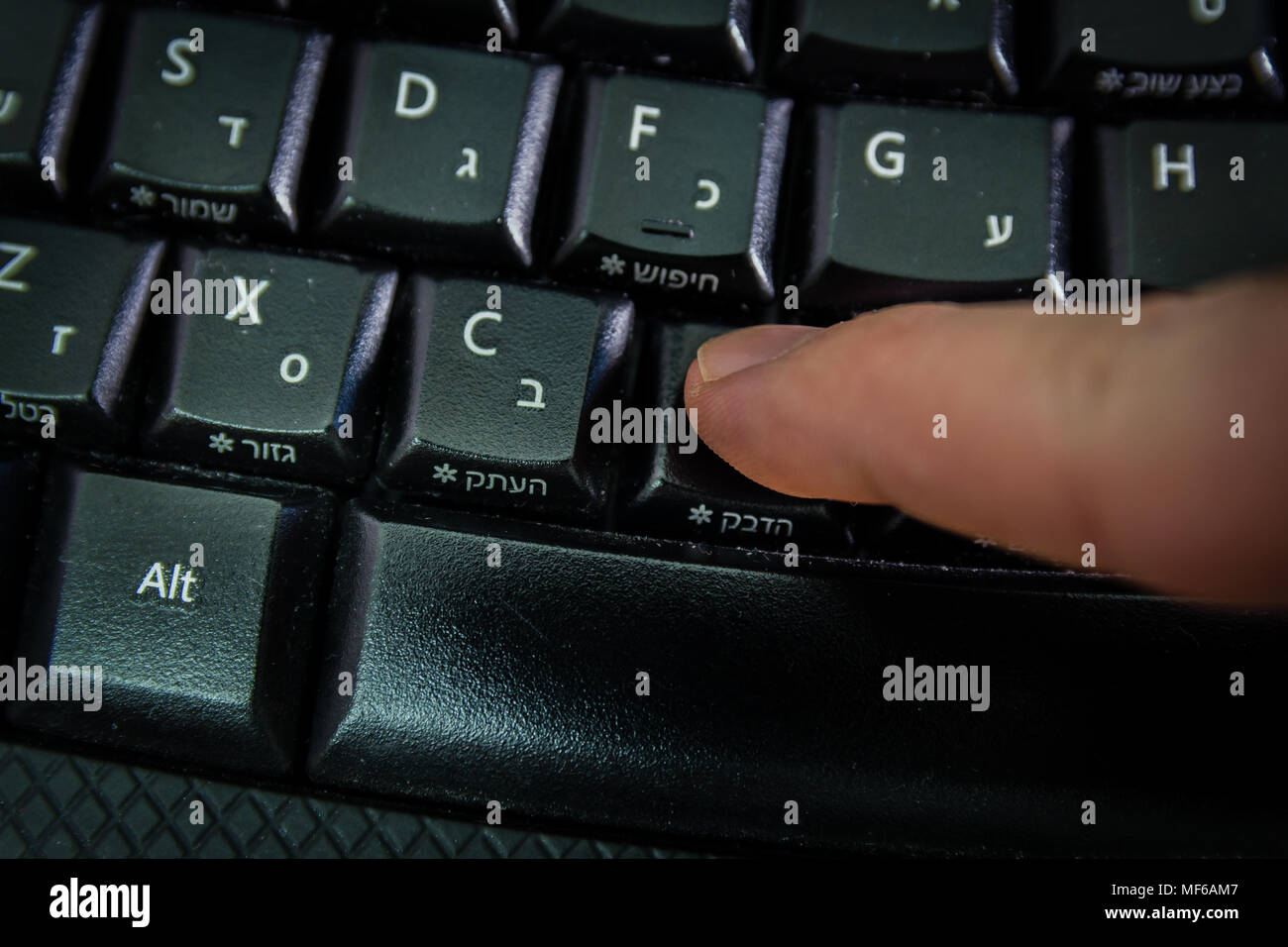 Man typing on a Wireless keyboard with letters in Hebrew and English ...