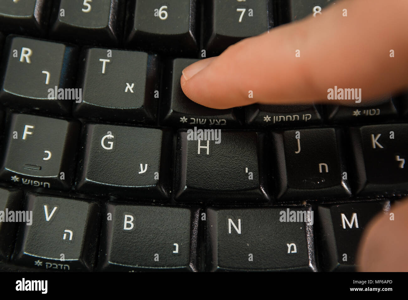 Man typing on a Wireless keyboard with letters in Hebrew and English ...