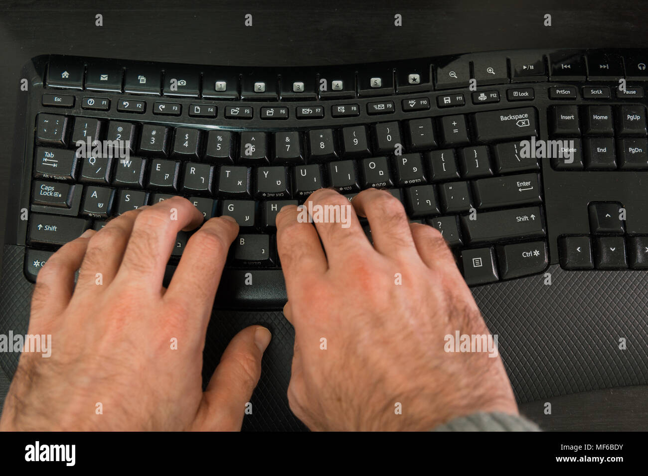 Man typing on a keyboard with letters in Hebrew and English - Wireless ...