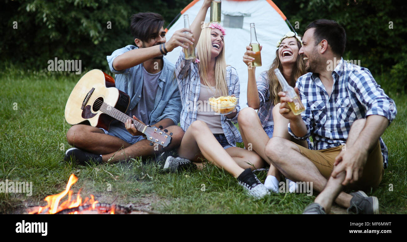 Group of friends camping and sitting around camp fire Stock Photo - Alamy