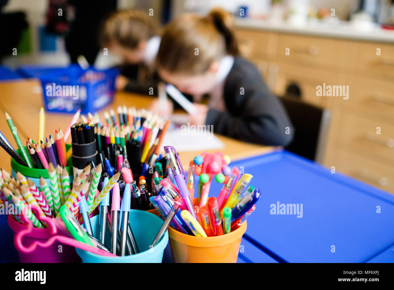 School children working in a classroom. They're sitting at a desk ...