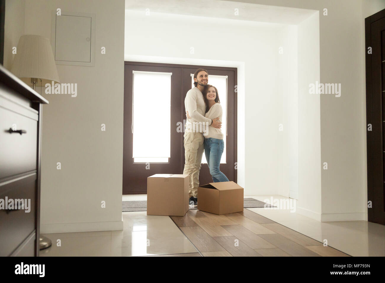 Couple embracing in hallway moving into new home with boxes Stock Photo ...