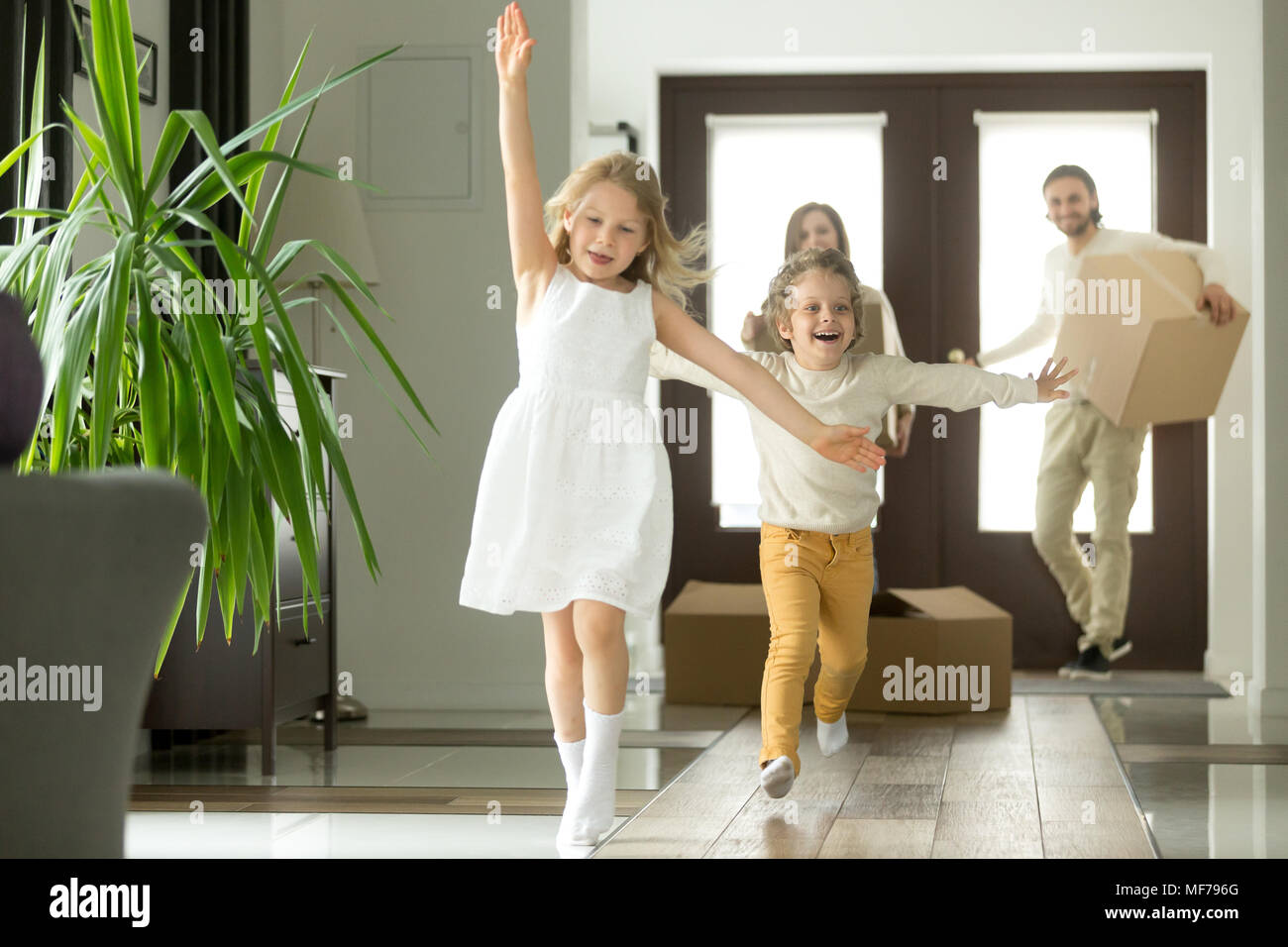 Excited funny kids running inside new house on moving day Stock Photo ...