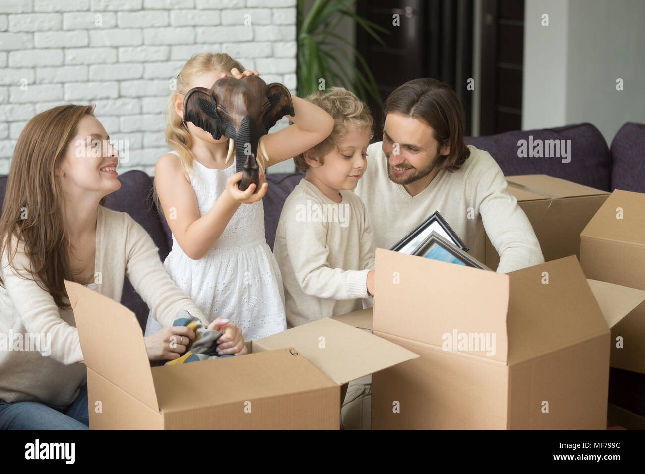 Kids helping parents unpacking boxes together moving in new home Stock ...
