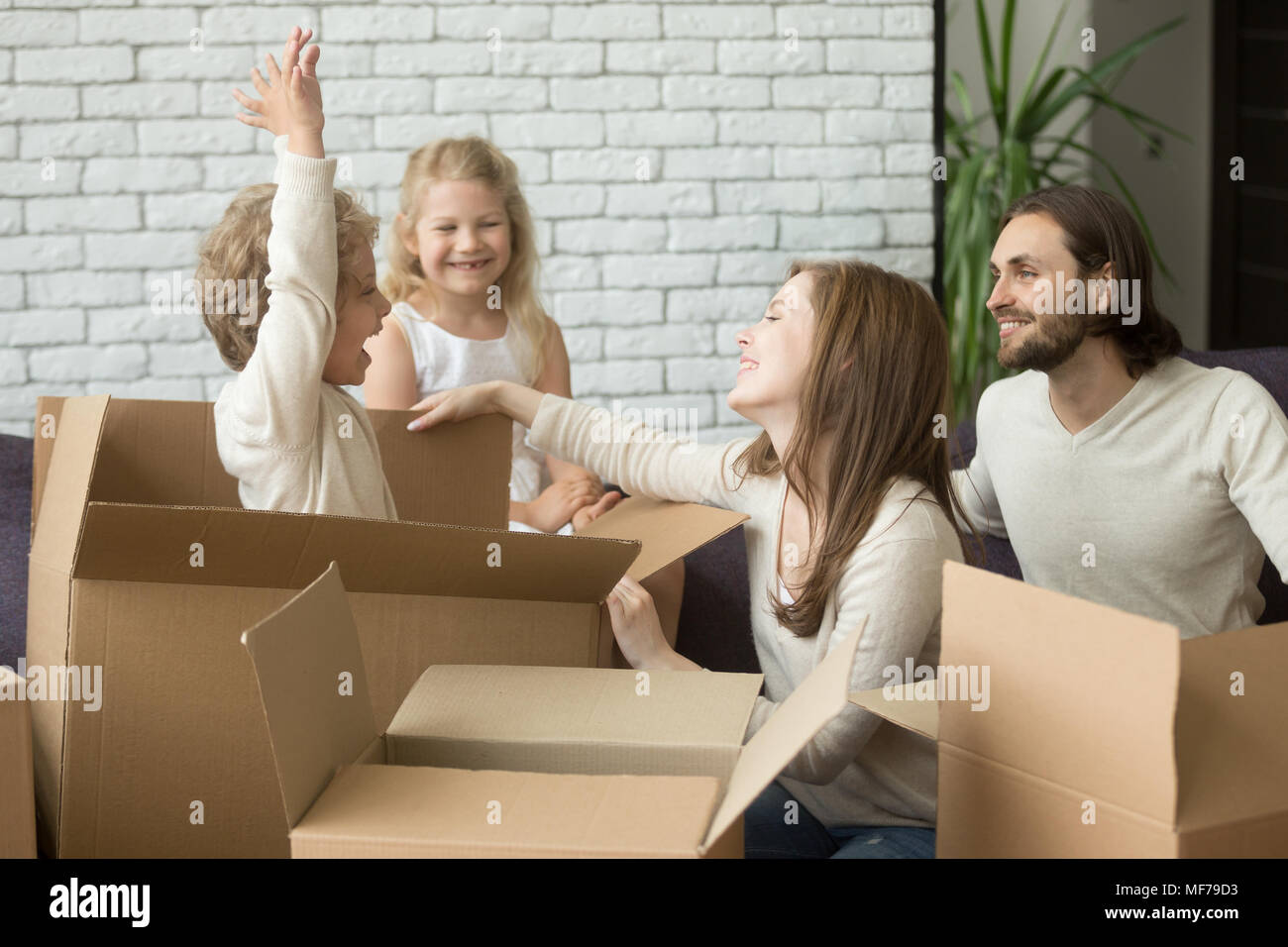 Happy boy jumping from box playing with family packing together Stock ...