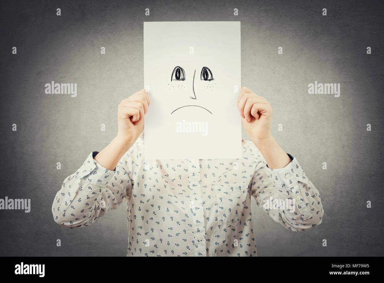 Young businesswoman covering her face using a sheet with drawn sad ...