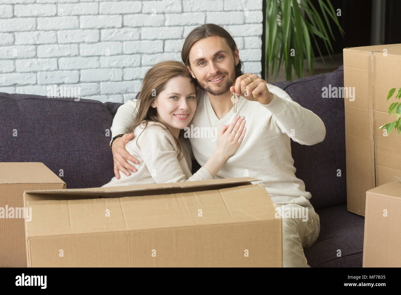 Happy couple holding keys looking at camera sitting on couch Stock ...