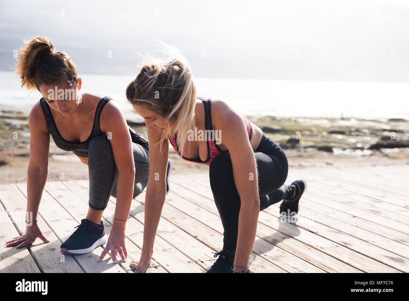 Beautiful young women exercising together outside in tights, crop tops ...