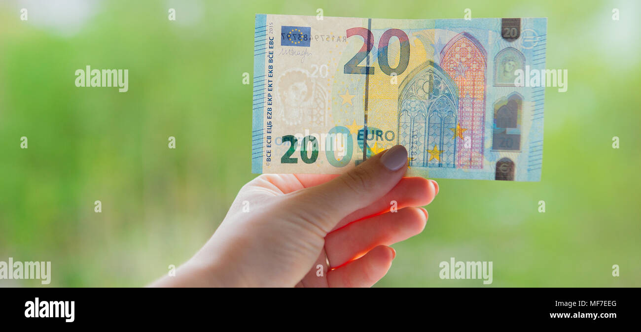 Hands holding 20 euro banknote on the green background. Check euro for ...