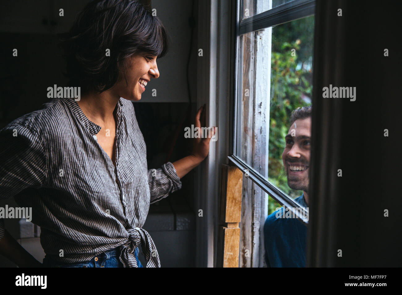 Happy couple smiling at each other through the window Stock Photo - Alamy