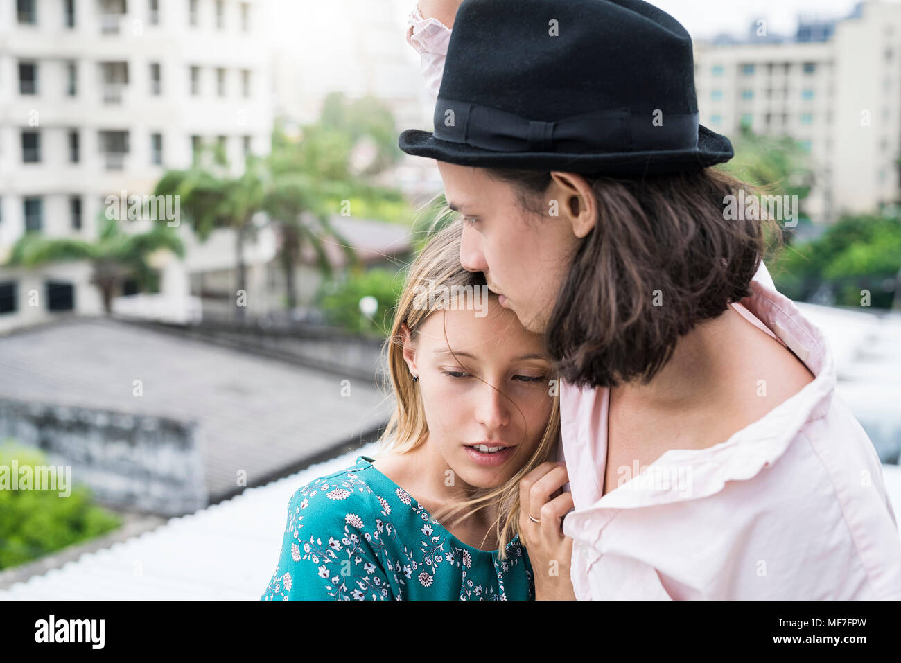 Young woman leaning against boyfriend on rooftop Stock Photo - Alamy