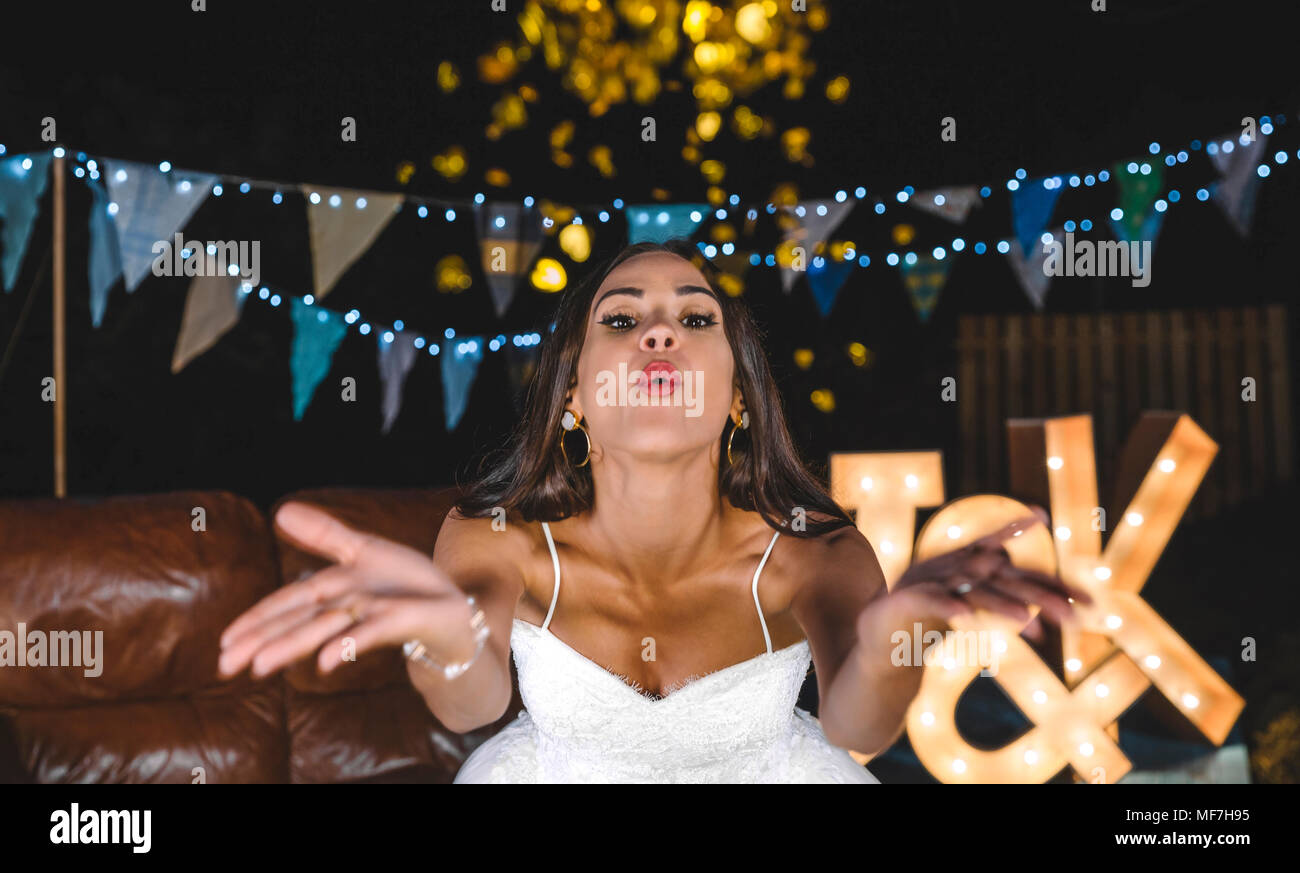 Portrait of happy bride blowing confetti on a night party outdoors ...