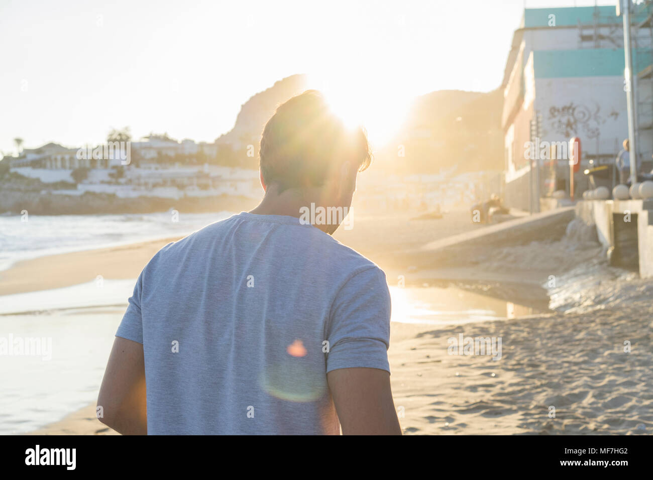 Back view of young man on the beach at sunset Stock Photo - Alamy