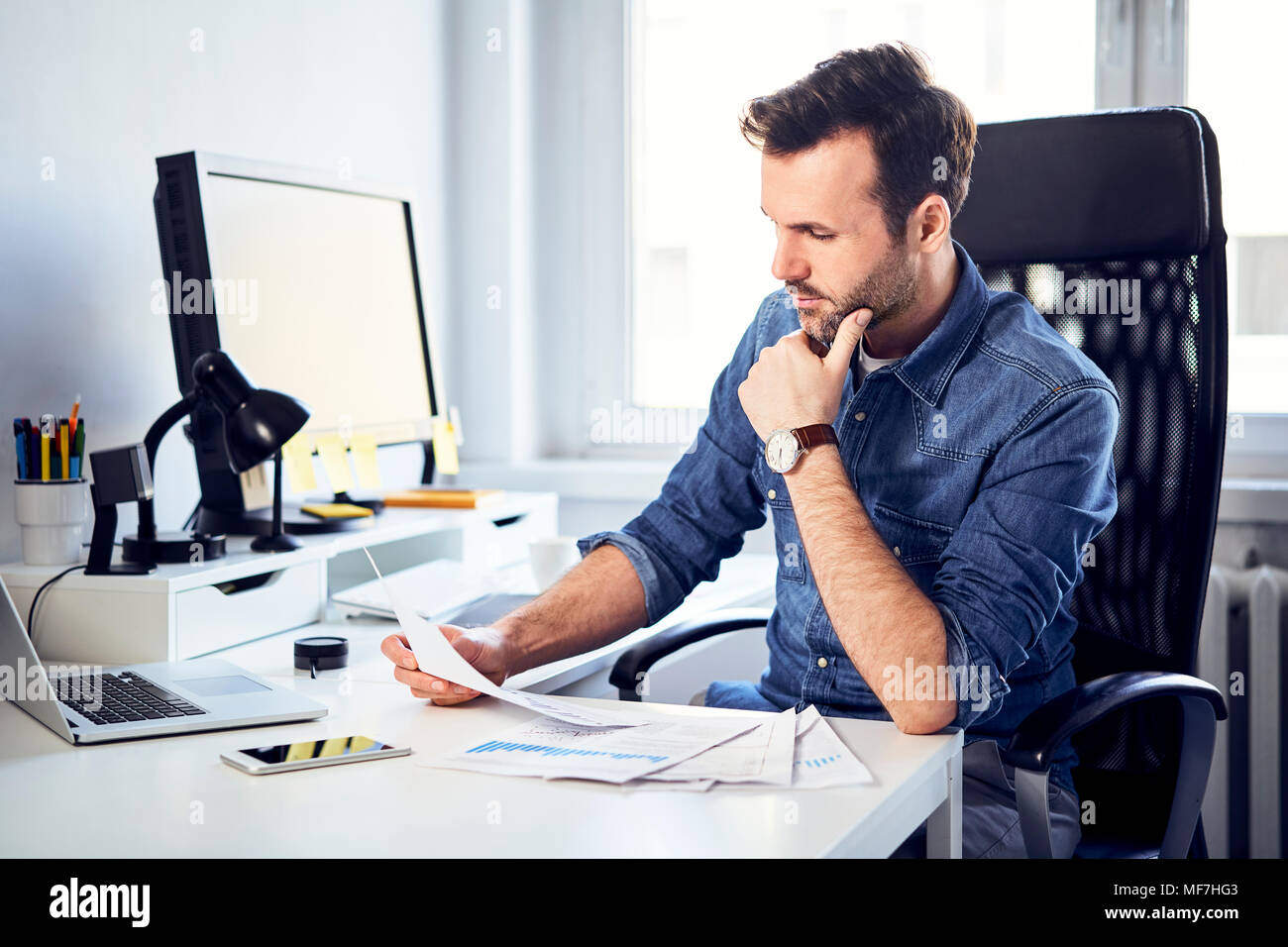 Man reading document at desk in office Stock Photo - Alamy