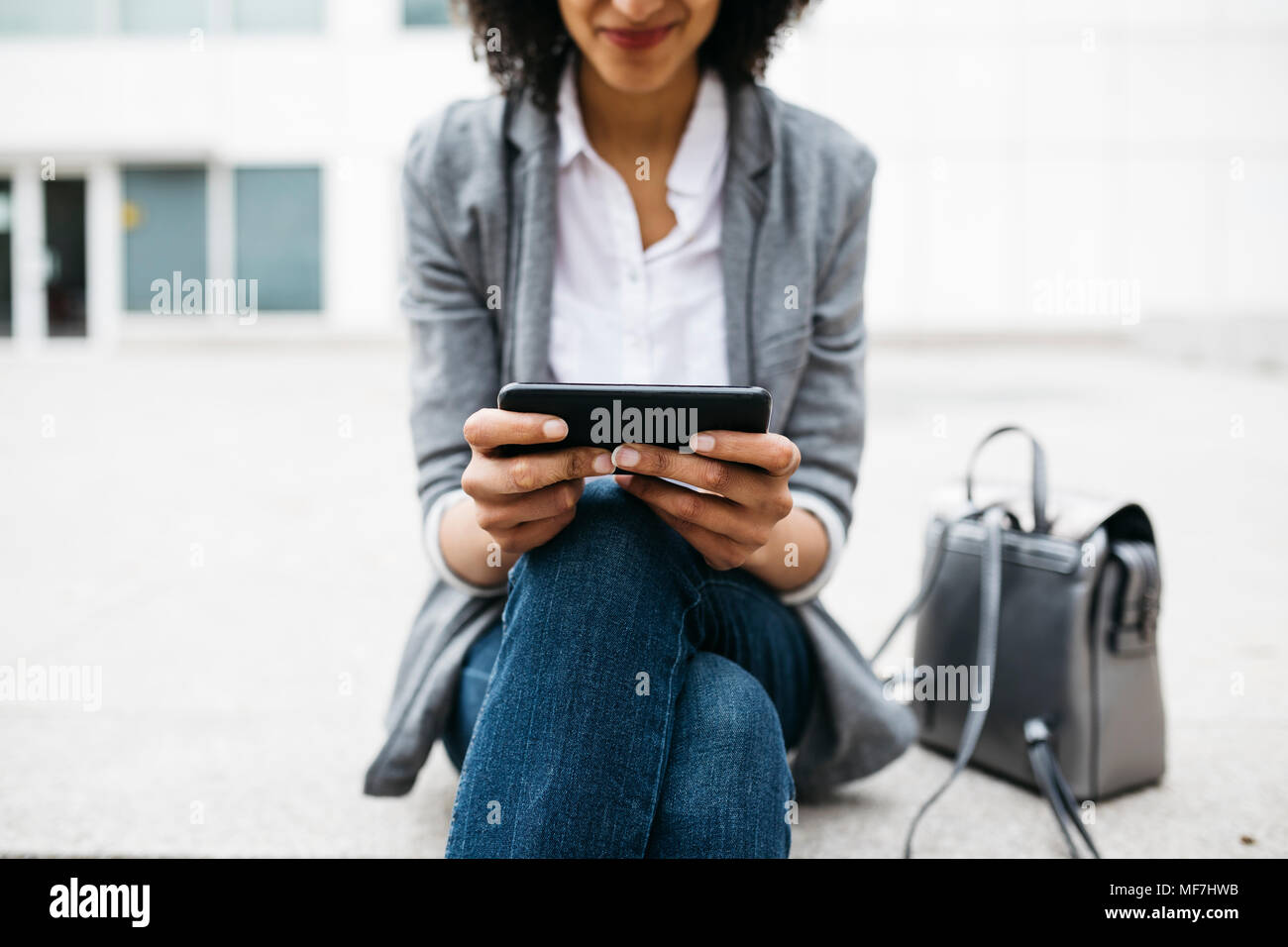 Woman sitting outdoors using cell phone Stock Photo - Alamy