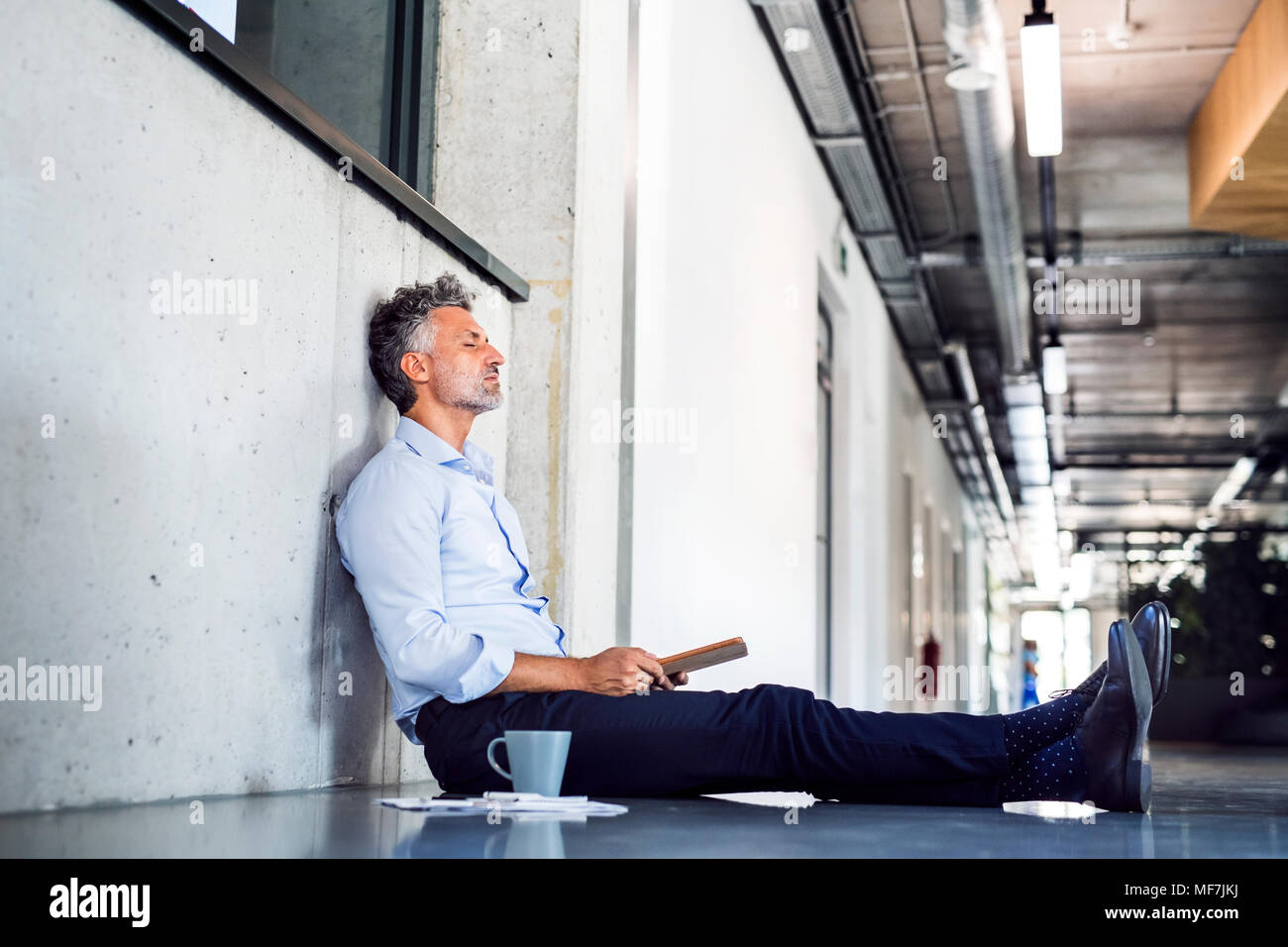 Mature businessman sitting floor leaning against wall hi-res stock ...