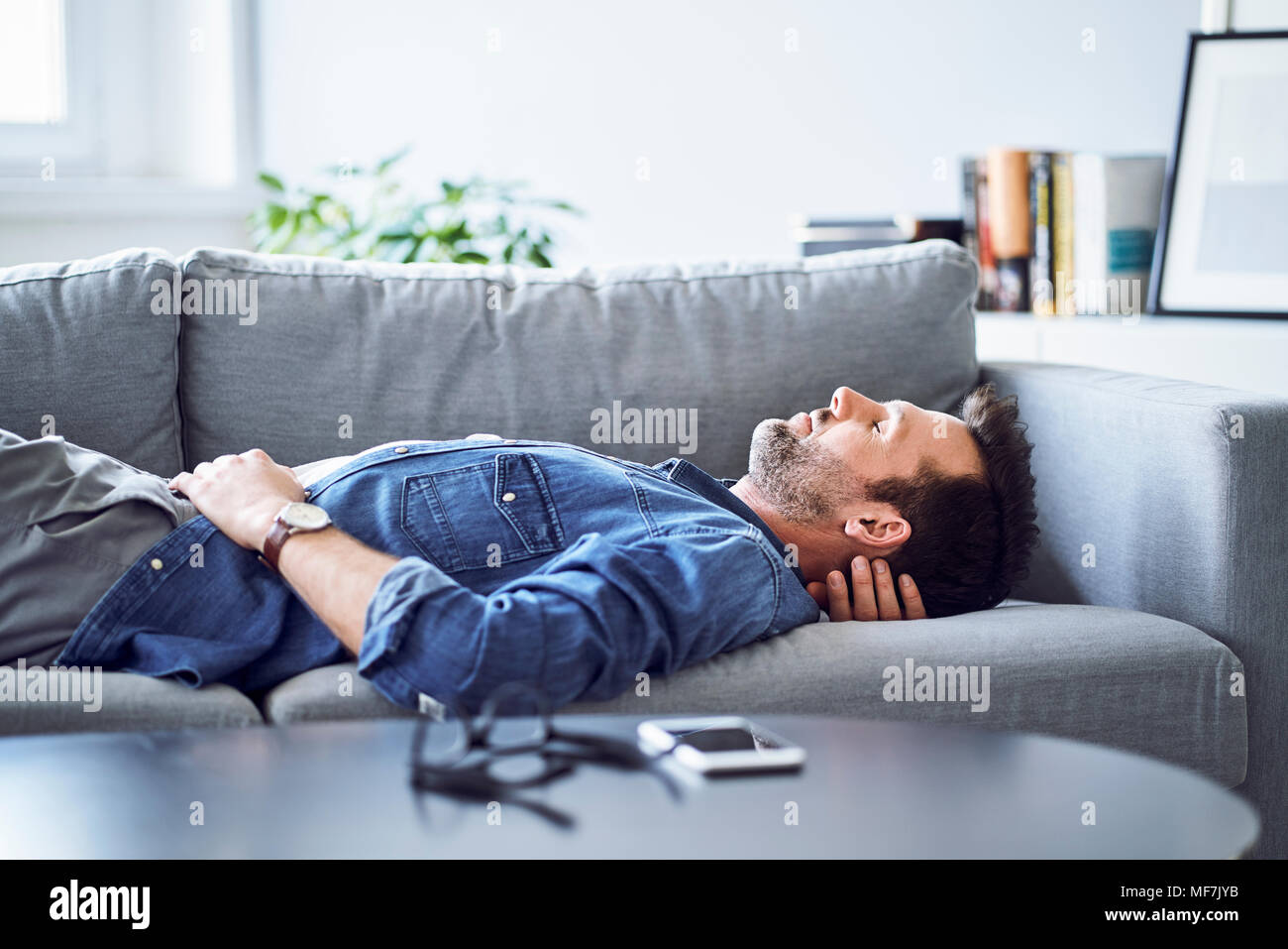 Relaxed man sleeping on sofa Stock Photo - Alamy