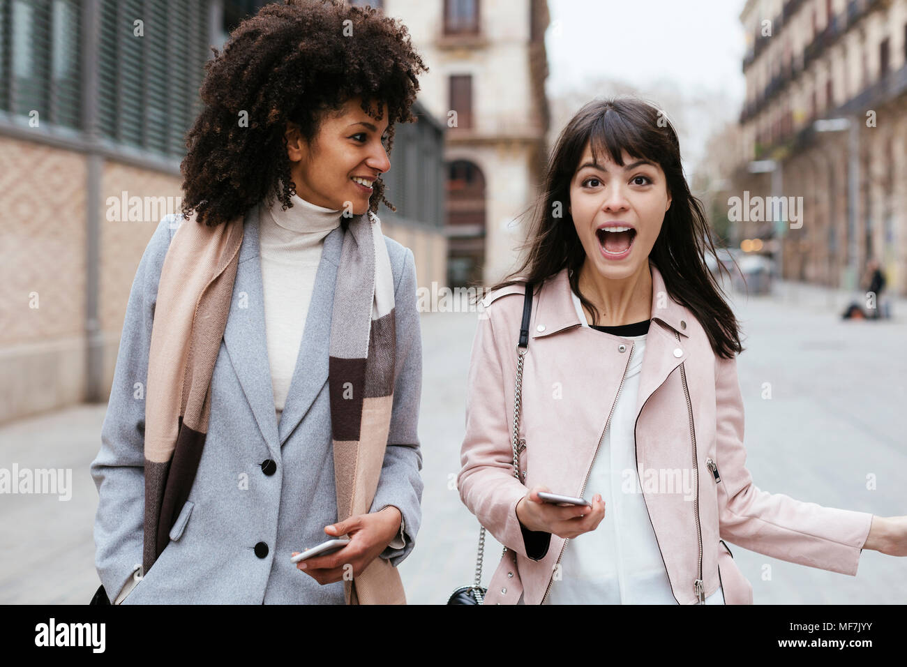 Two female friends with cell phones in the city hi-res stock ...