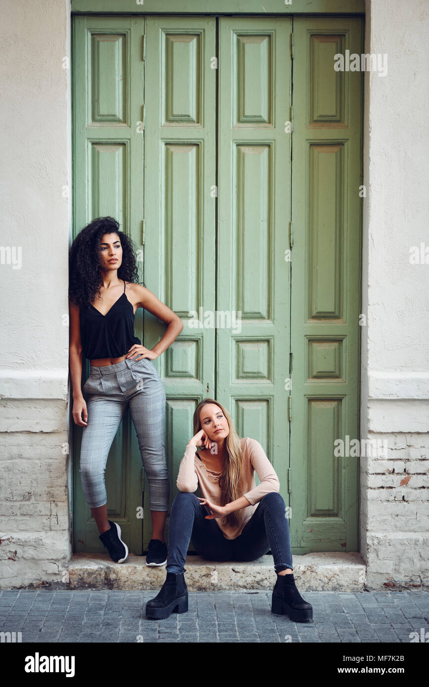 Two women waiting in front of an entrance door Stock Photo - Alamy