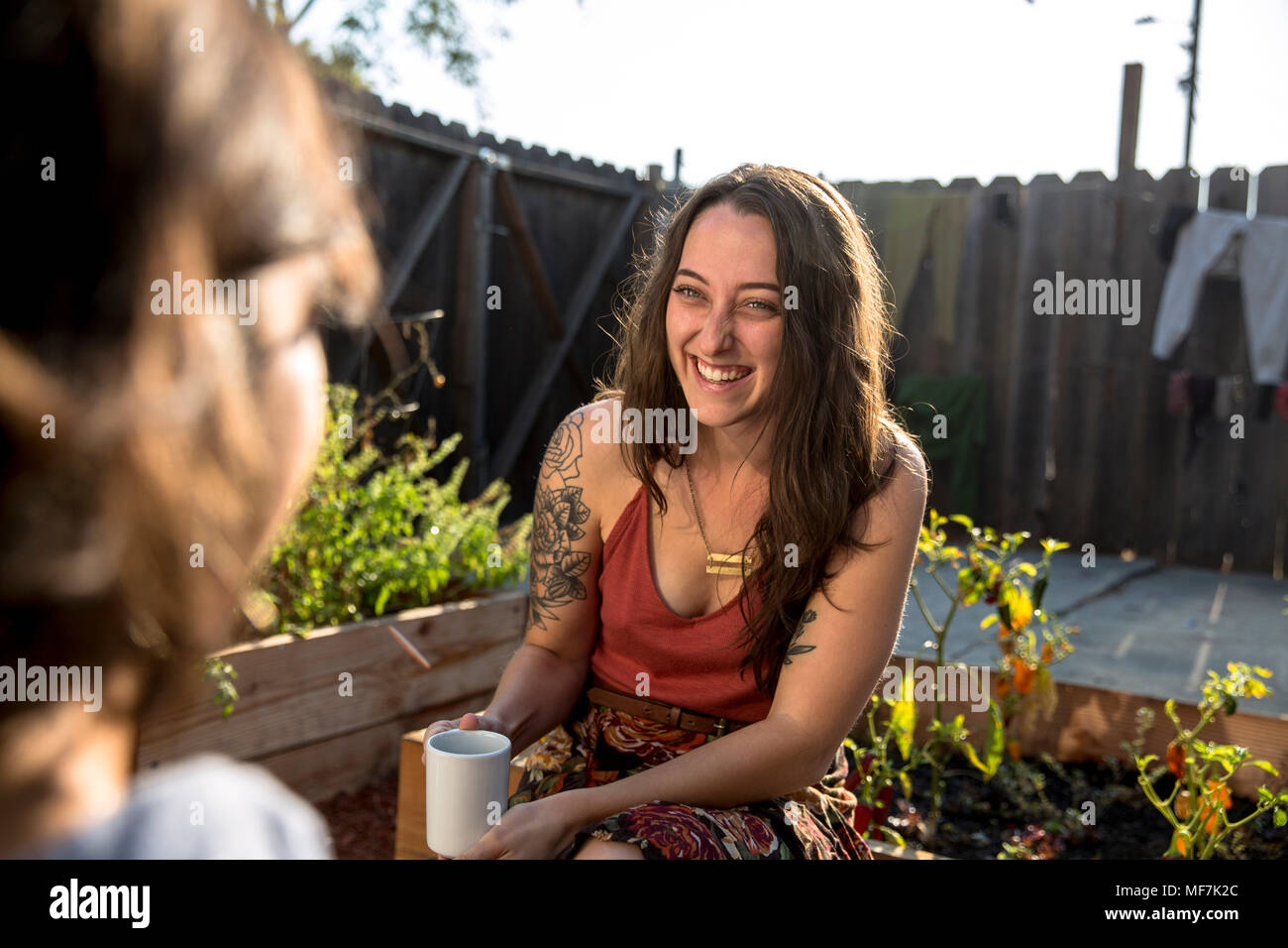 Two happy young women talking in backyard Stock Photo - Alamy