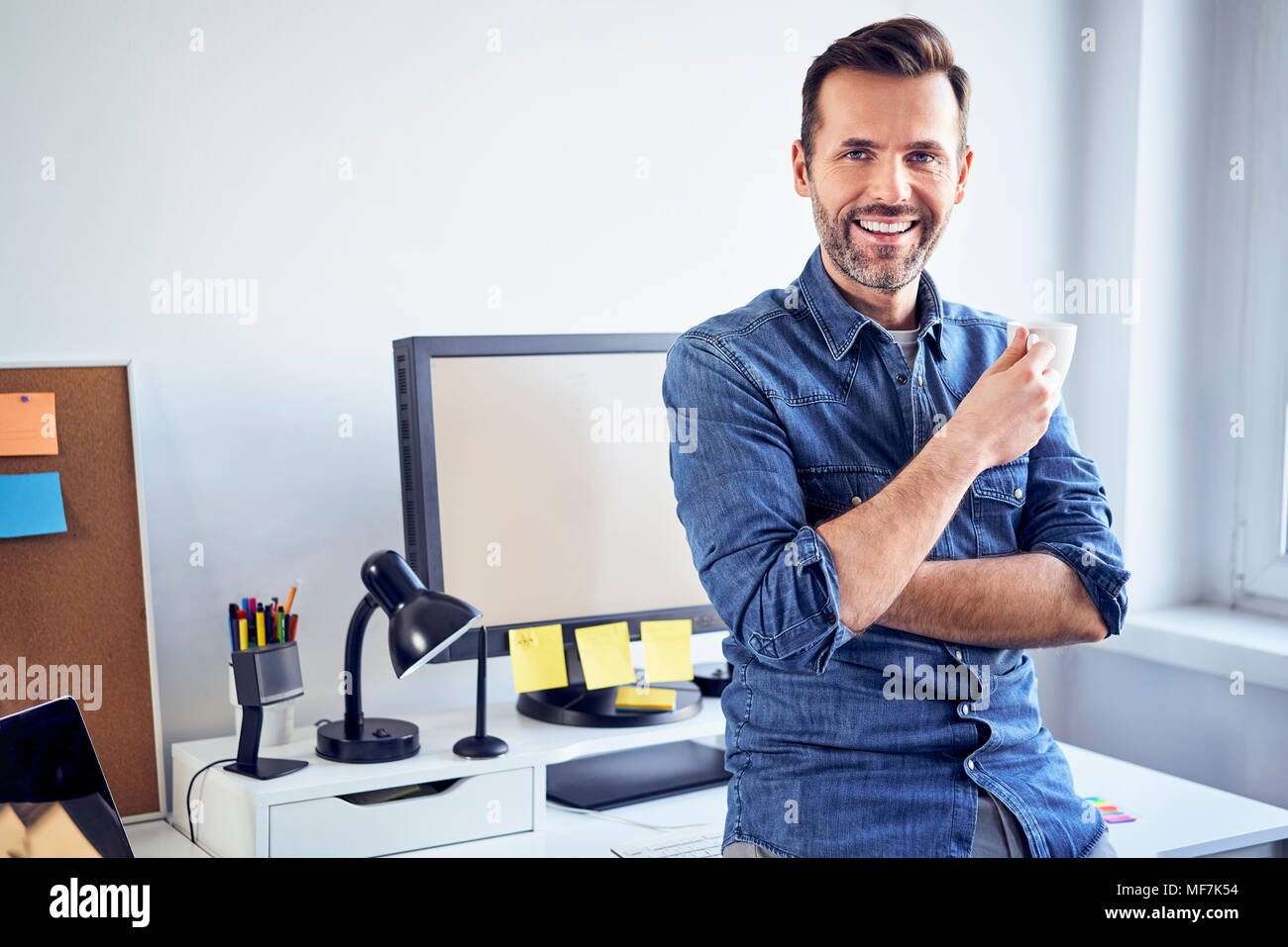 Portrait of smiling man with cup of coffee at desk in office Stock ...