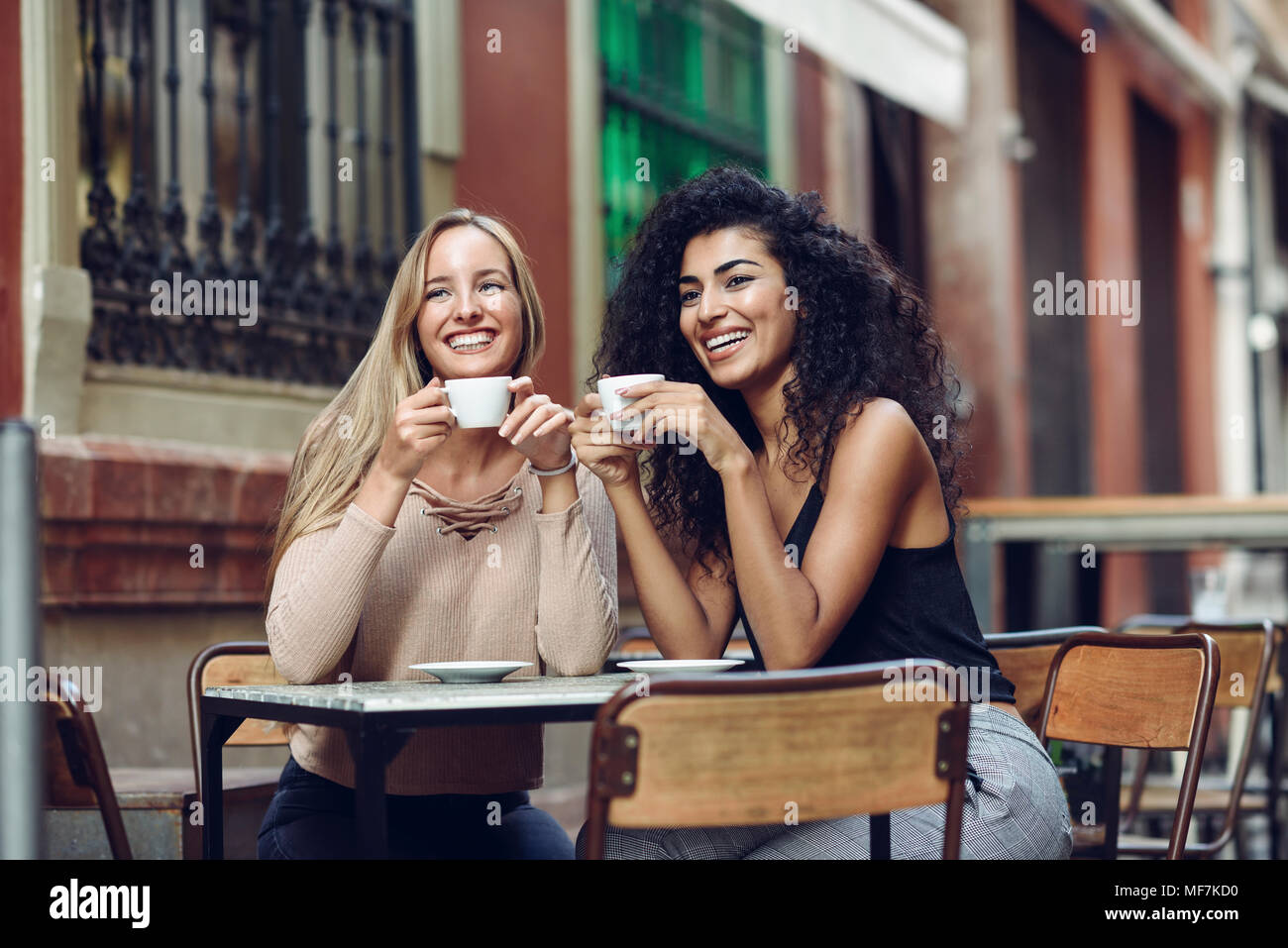 Two happy friends drinking coffee in sidewalk cafe Stock Photo - Alamy