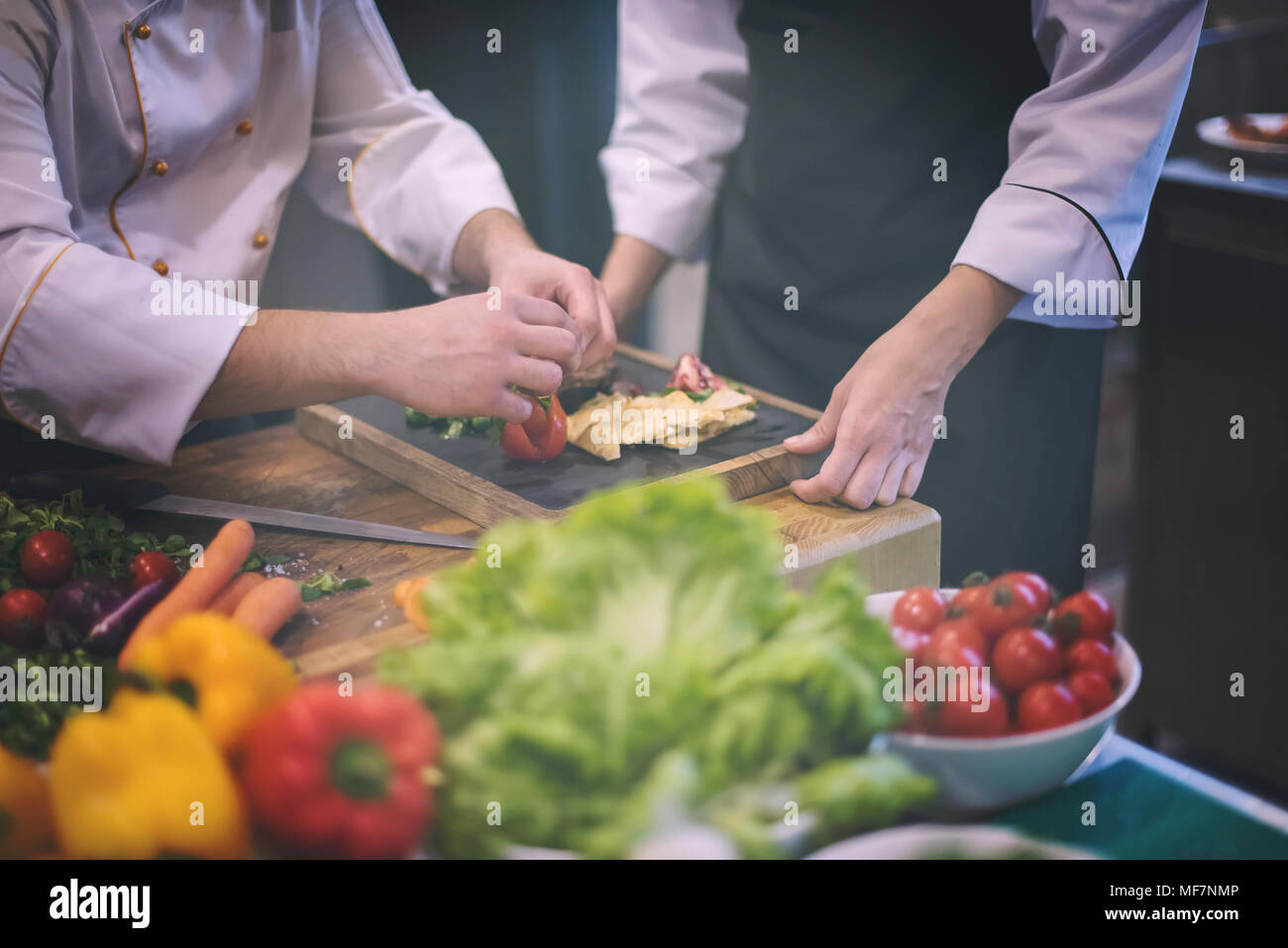 Professional team cooks and chefs preparing meal at busy hotel or ...