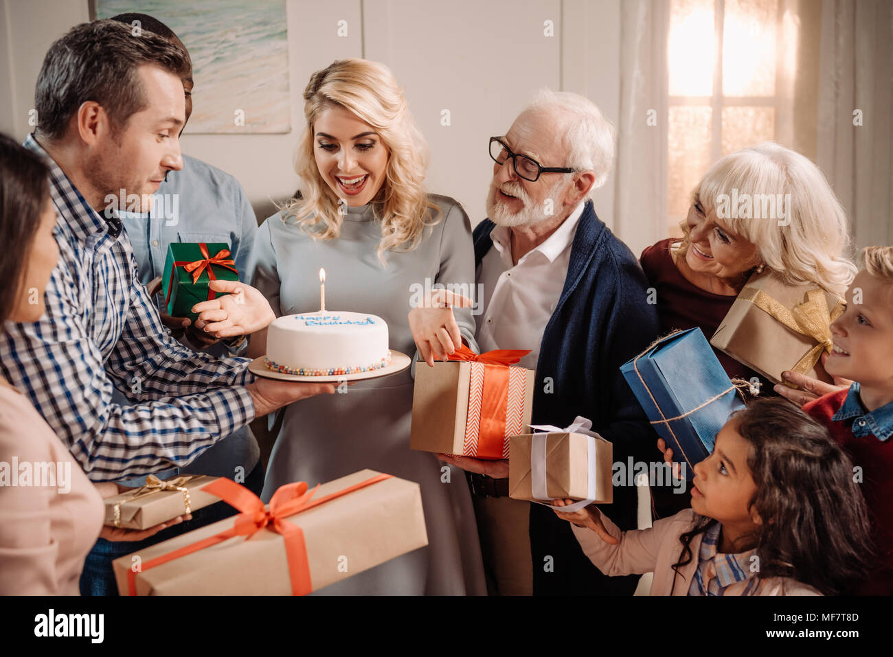 family presenting cake and gifts to woman Stock Photo - Alamy