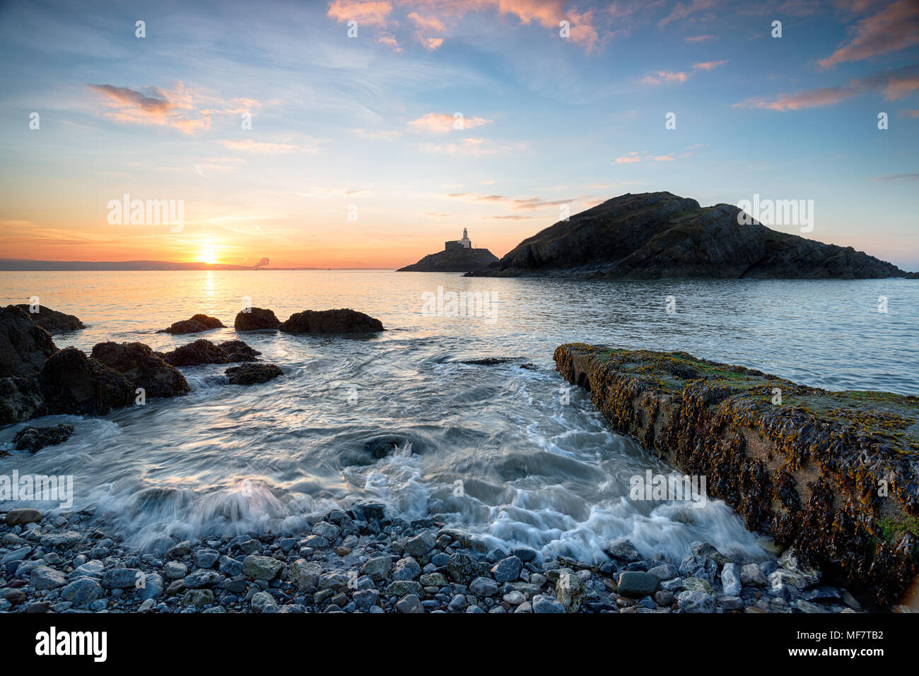 Beautiful sunrise over the lighthouse at The Mumbles on the south coast ...