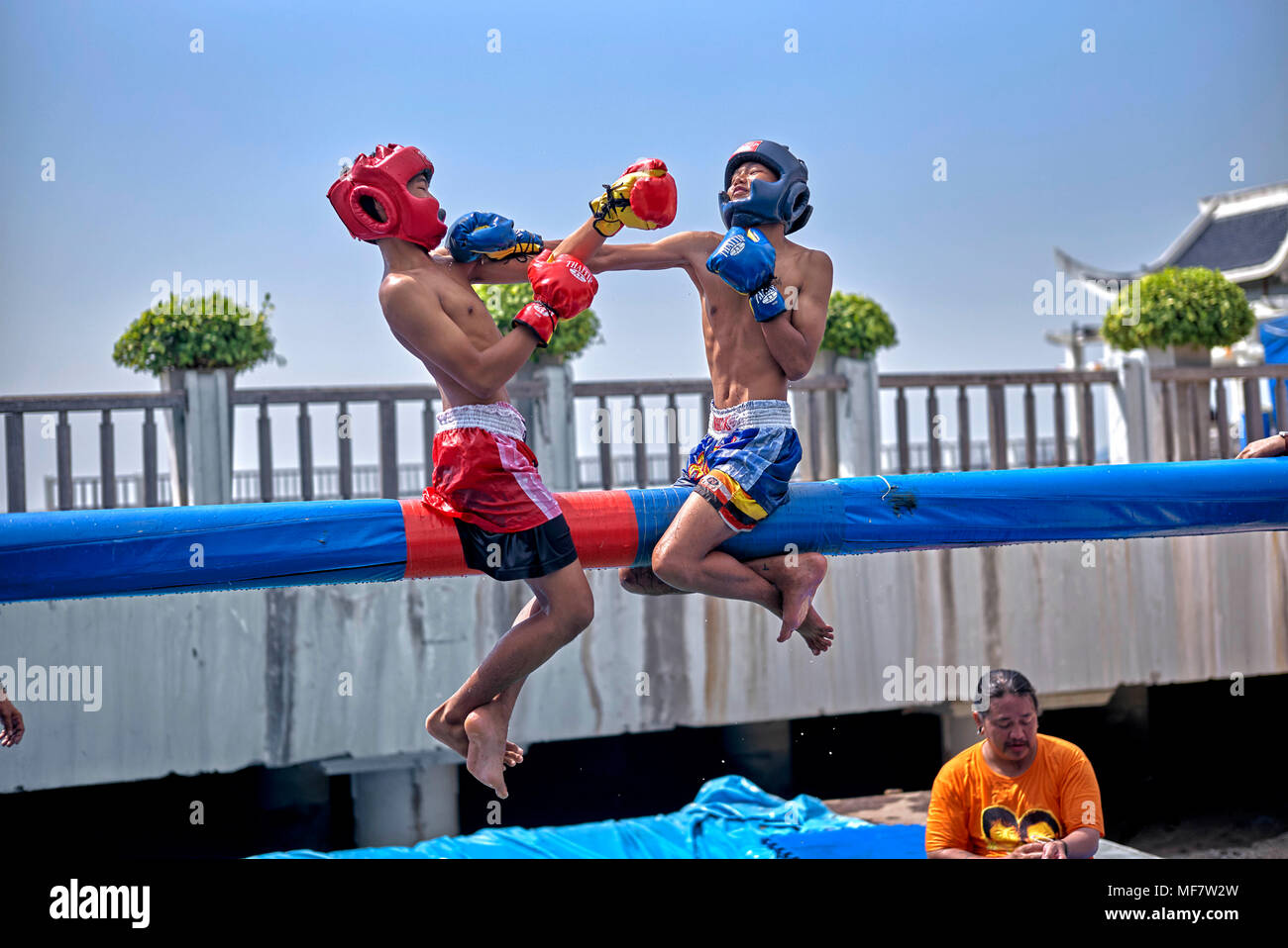 Unusual sport. Muay Thai fighters competing on a Battle Beam perched ...