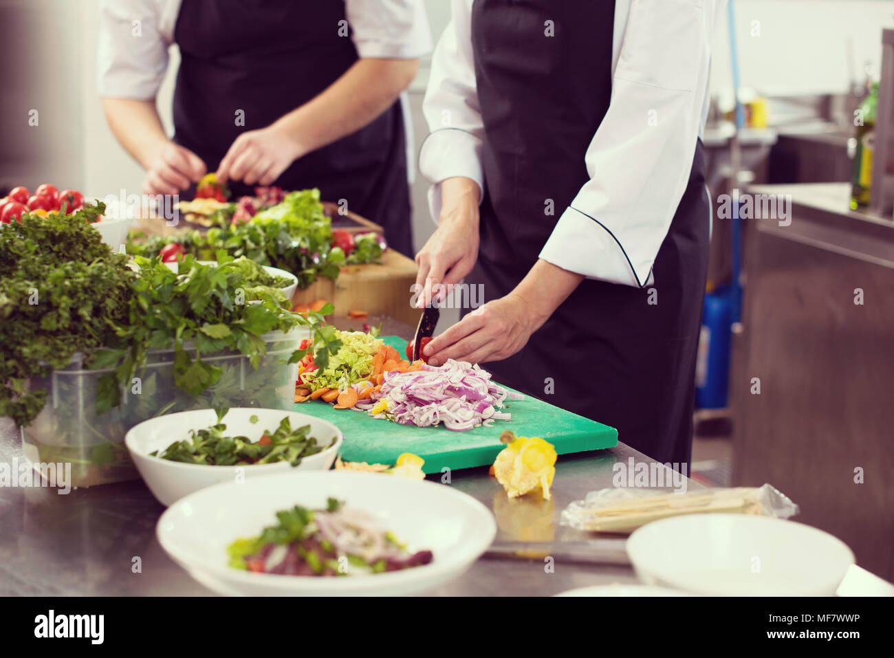 Professional team cooks and chefs preparing meals at busy hotel or ...