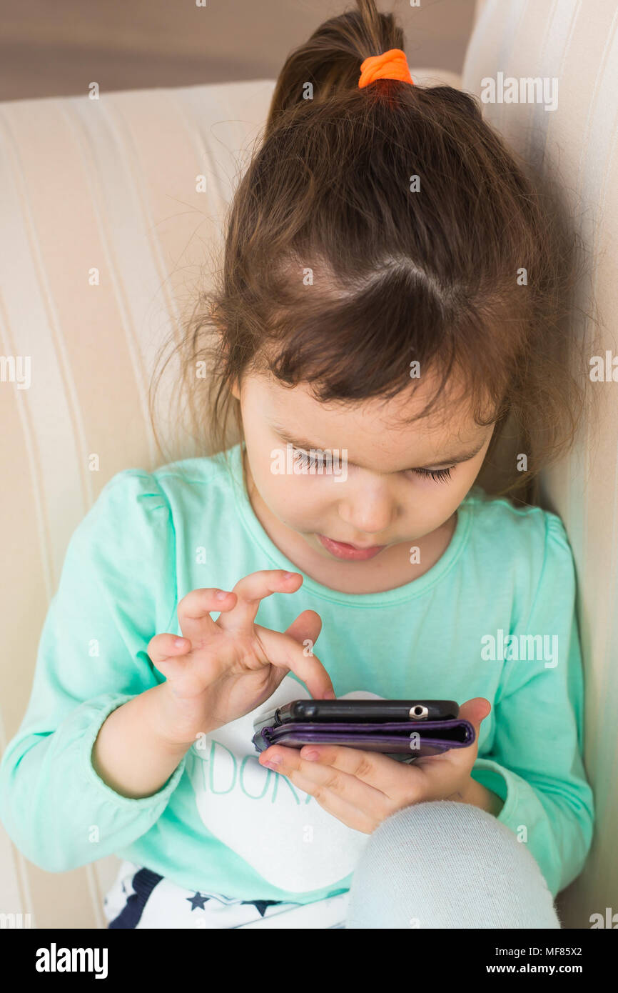 Cute little girl using modern smartphone indoors Stock Photo - Alamy