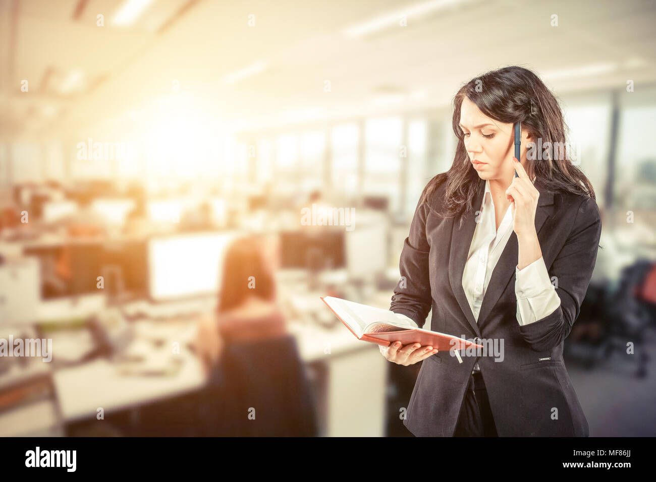 young business woman holding notepad and talking on mobile phone on the ...