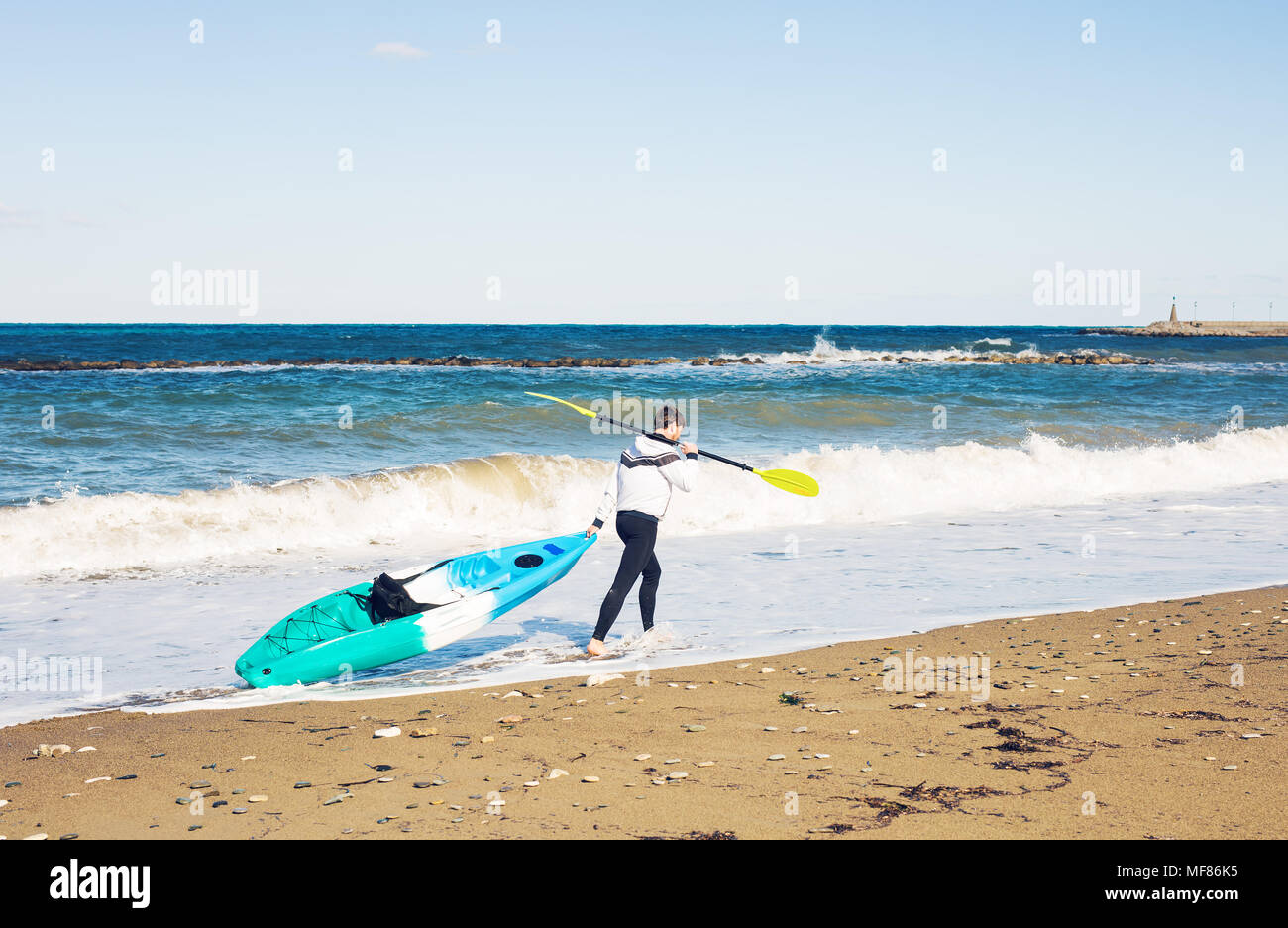 man carrying kayak at sea beach Stock Photo - Alamy