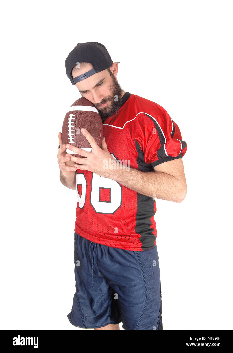 A handsome young football player standing with his ball in his hand ...