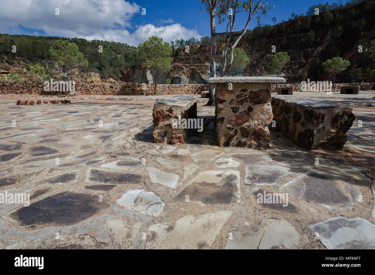 Tables and seats of stones with the forest Stock Photo - Alamy
