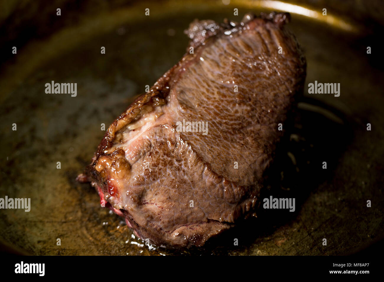 An ox cheek from a supermarket being browned in a copper frying pan ...