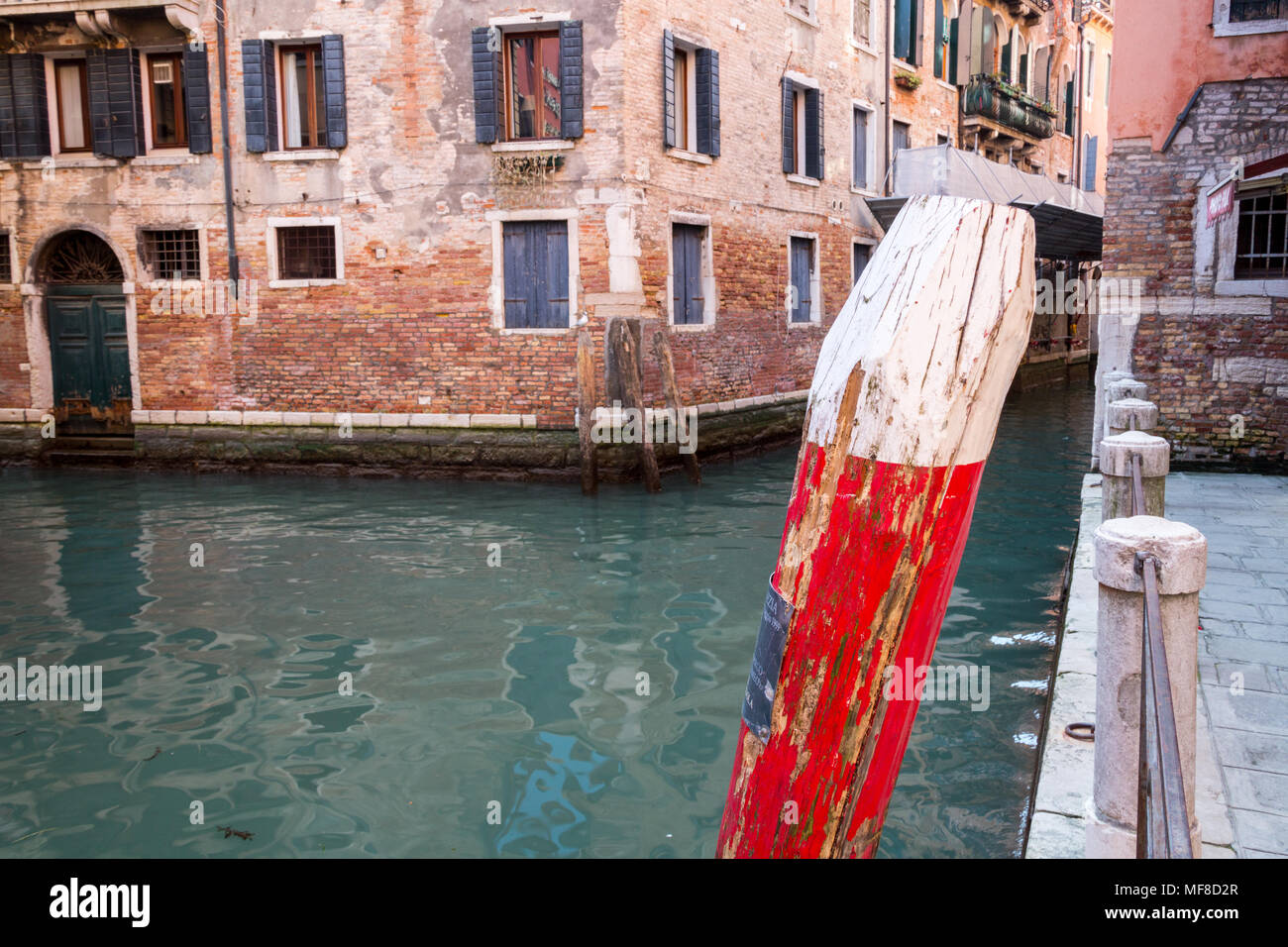 Venice, Italy - February 28, 2015: A colorful mooring post stands out ...