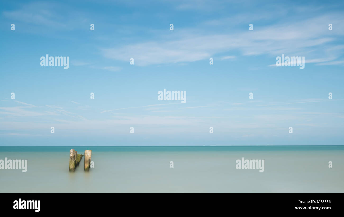 Quiet calm sea and a blue sky with some clouds and poles Stock Photo ...