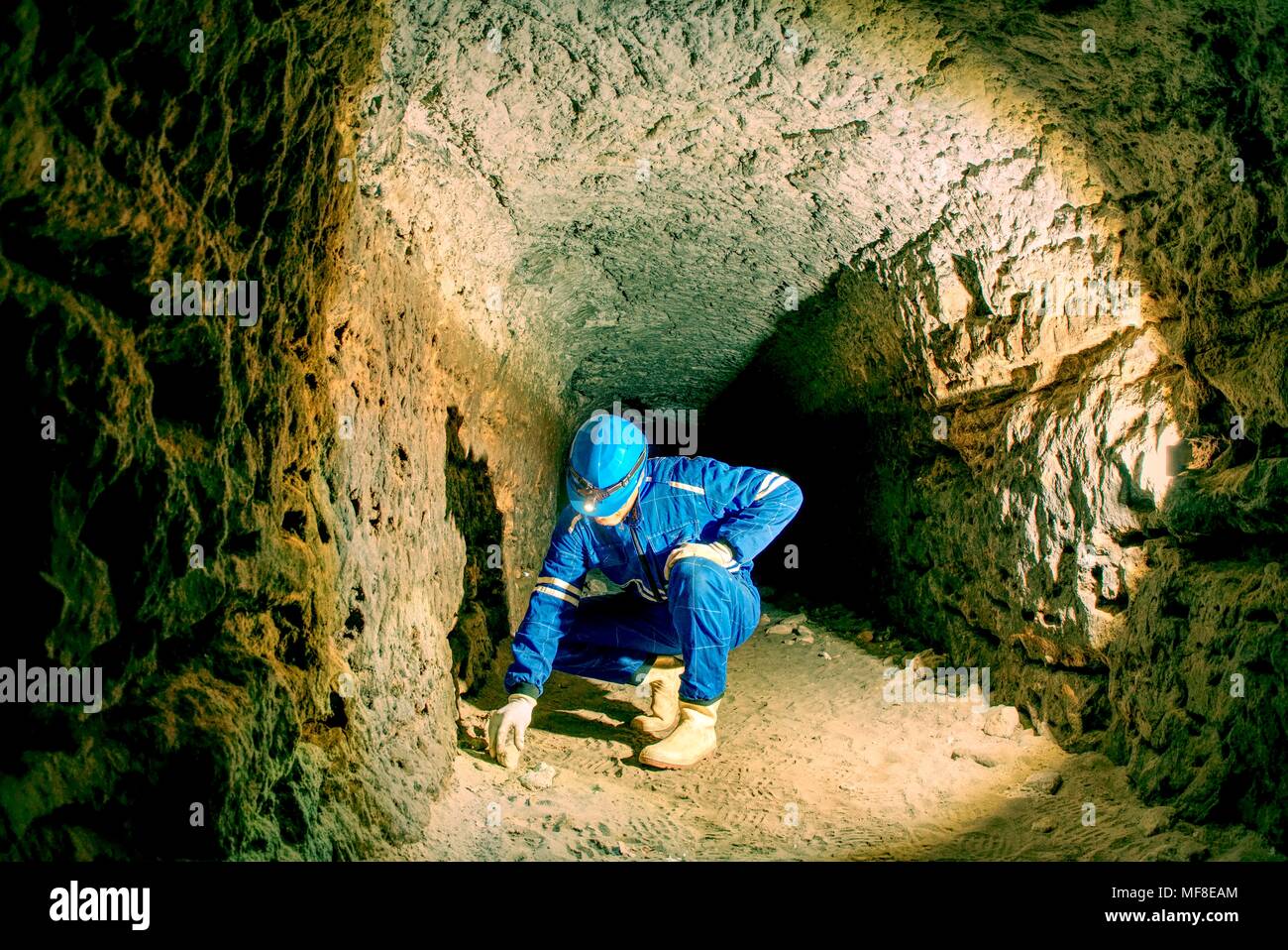 Man works in mystical ancient long tunnel from orange sandstone walls ...