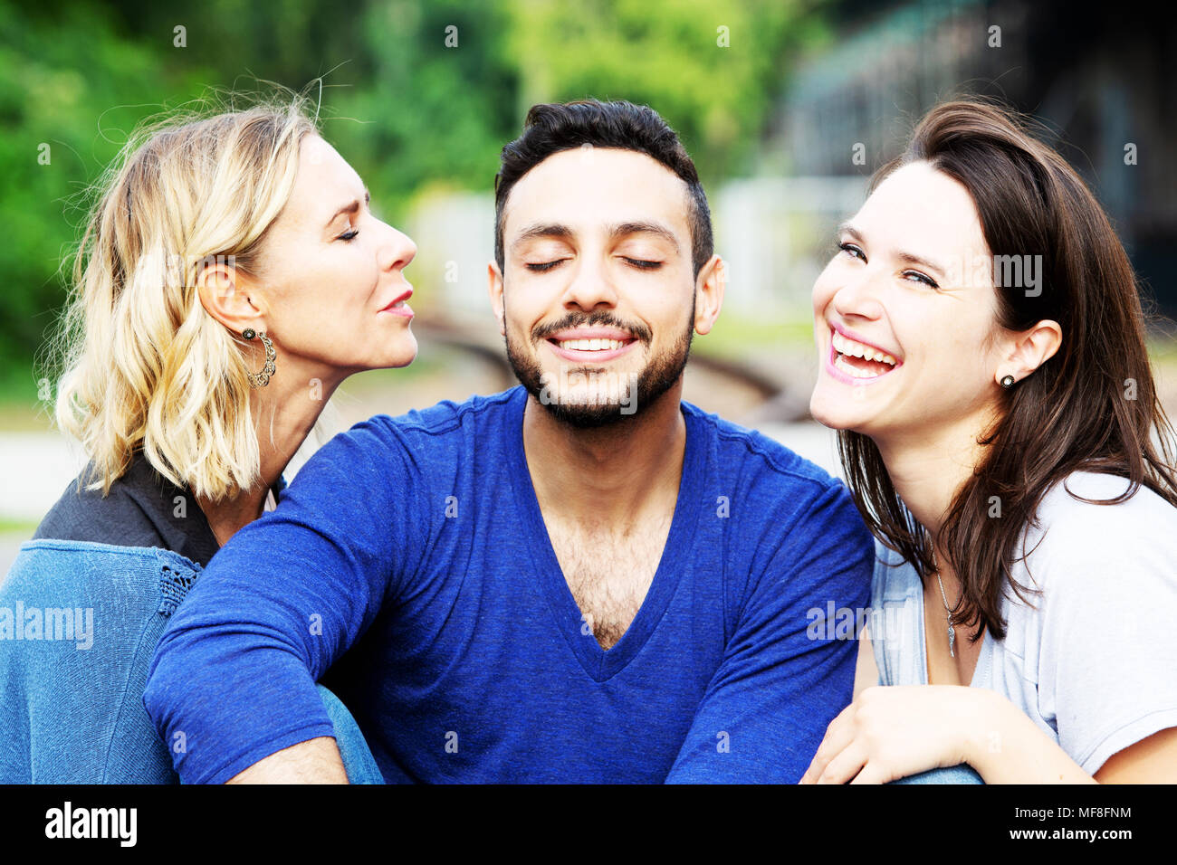 two beautiful women kissing handsome man on his cheeks Stock Photo - Alamy