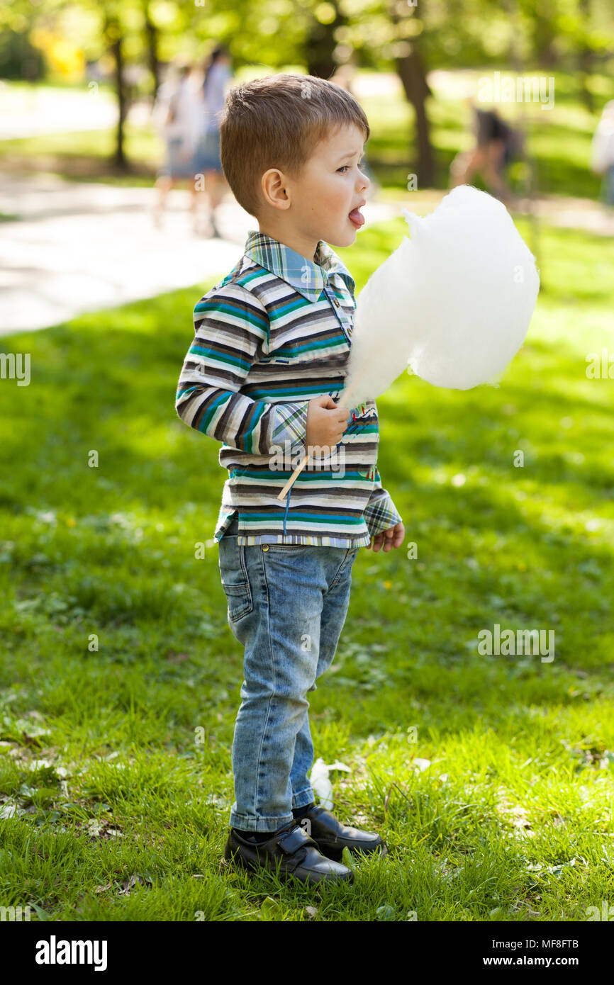 Adorable little boy eating white sweet cotton candy Stock Photo - Alamy