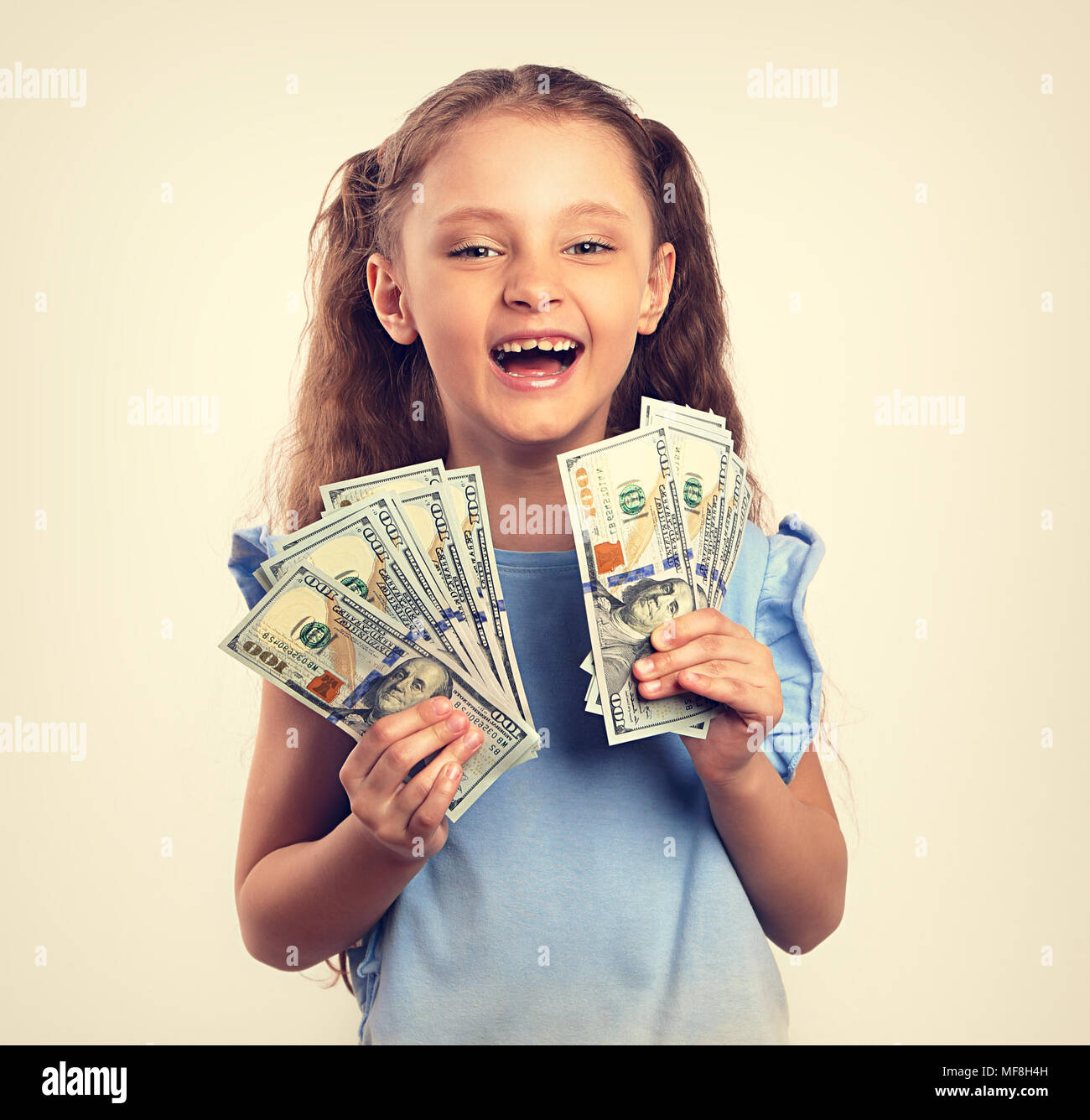 Happy laughing rich kid girl holding money in the hand. Vintage toned ...
