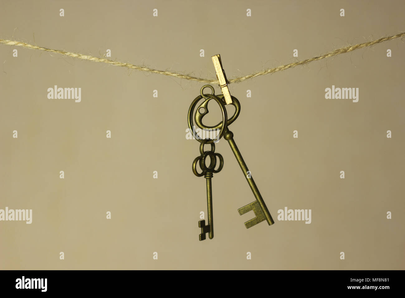 Vintage key hanging on a rope on a gold background Stock Photo - Alamy