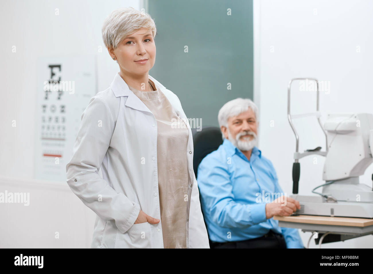 Doctor ophthalmologist staying in front of old patient in medical ...